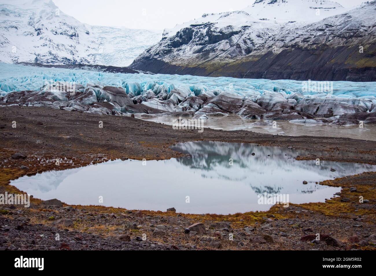 Bright blue Icelandic glacier with layers of glacier, volcanic ash ...