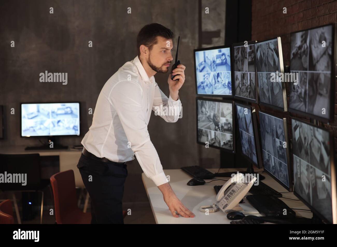 Male security guard using radio transmitter in surveillance room Stock ...