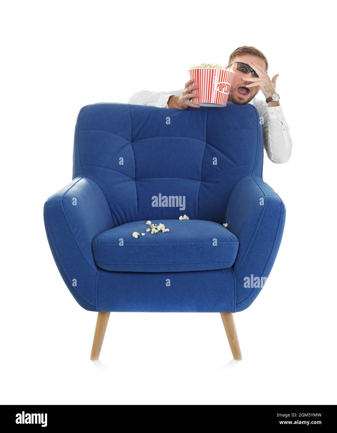 Scared man with 3d glasses and popcorn hiding behind armchair during ...