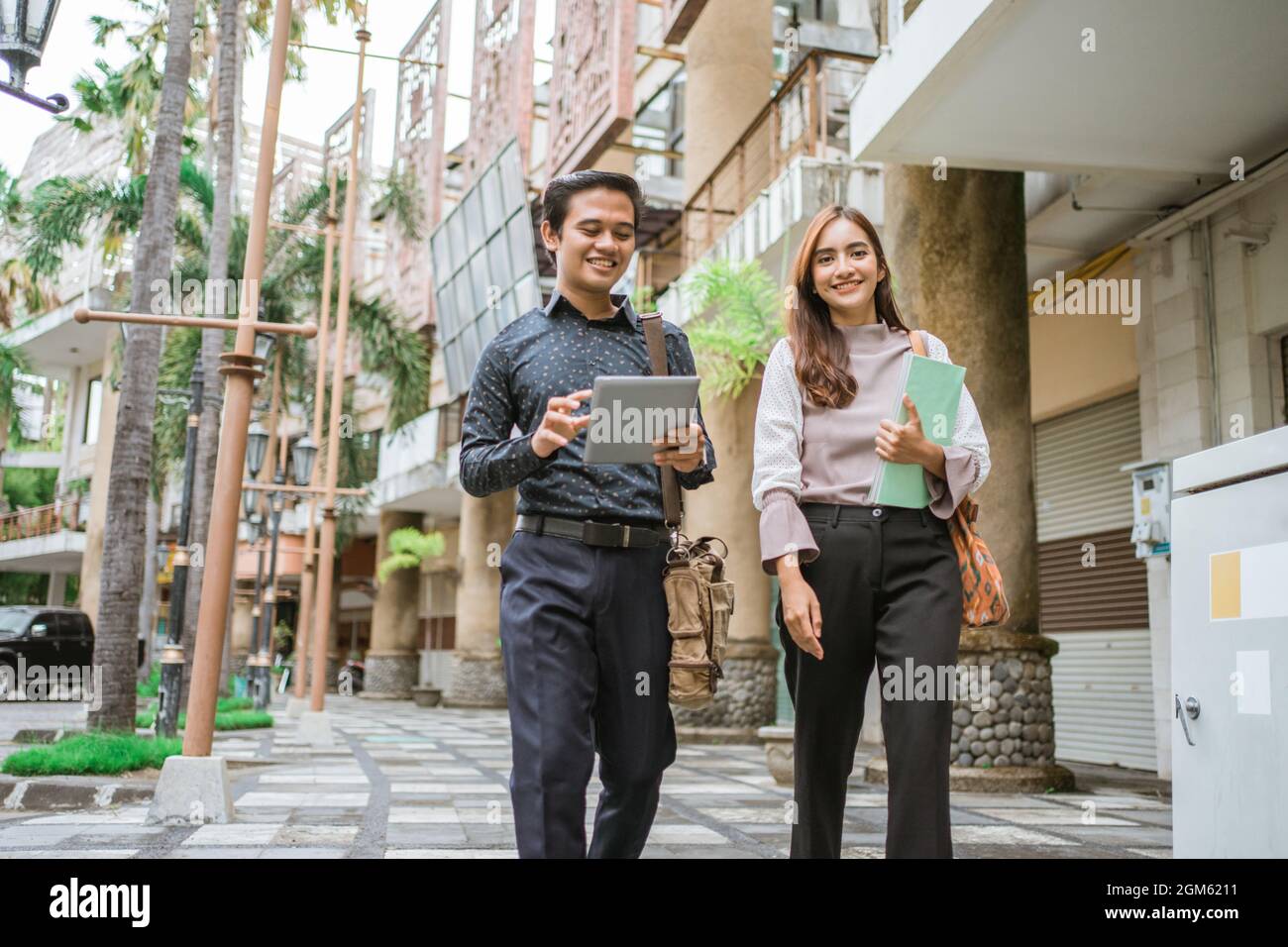 Business man and woman walking trough sidewalk smiling going to office ...