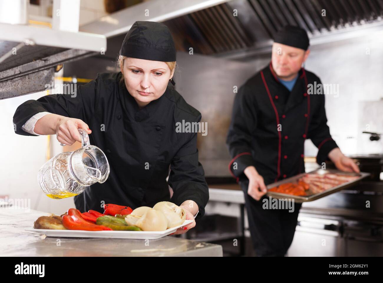 Female chef seasoning dish with oil Stock Photo - Alamy
