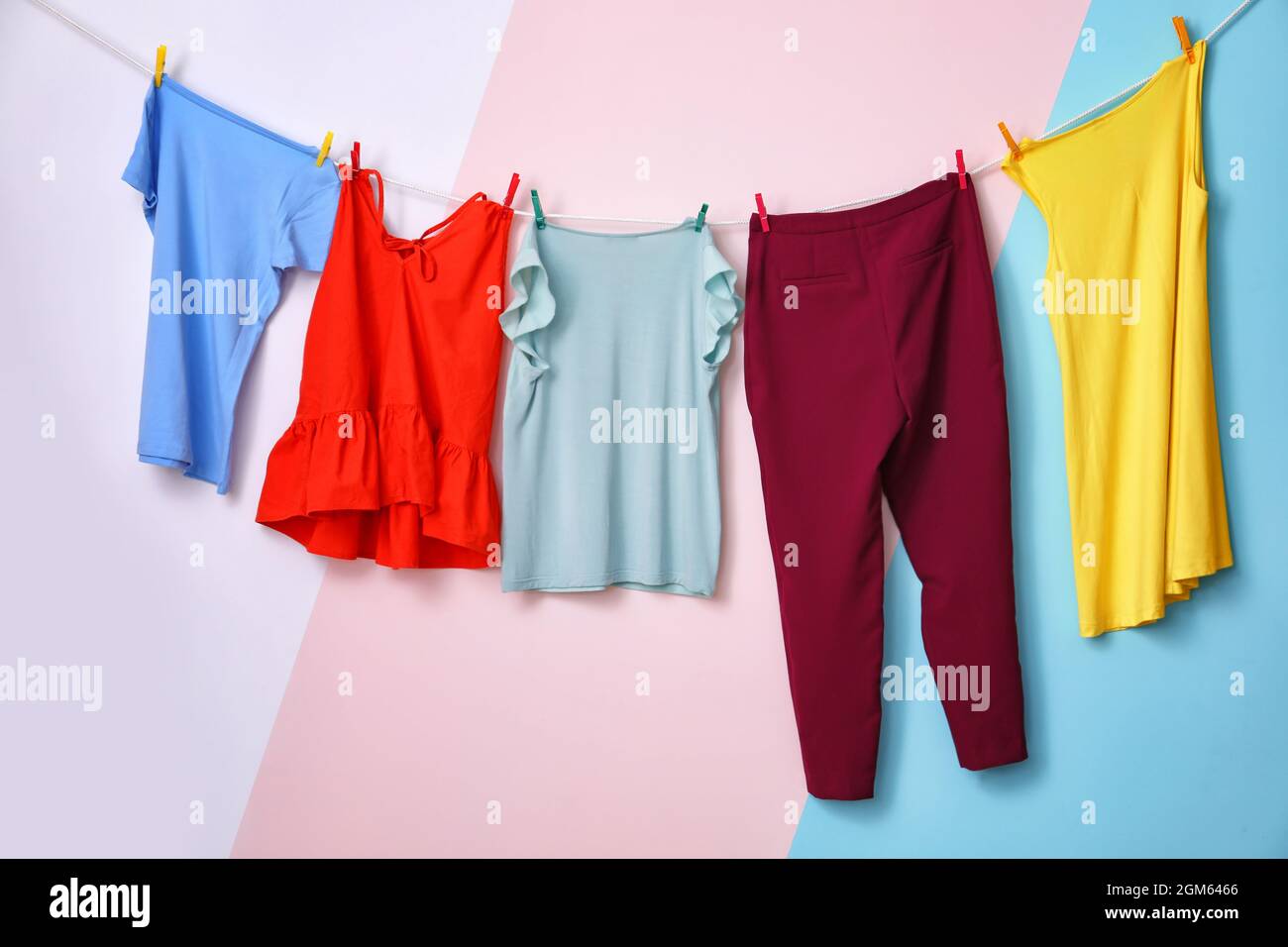 Rope with rainbow clothes on color background Stock Photo - Alamy