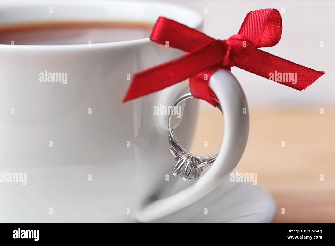 Engagement ring tied to cup of coffee, closeup Stock Photo - Alamy