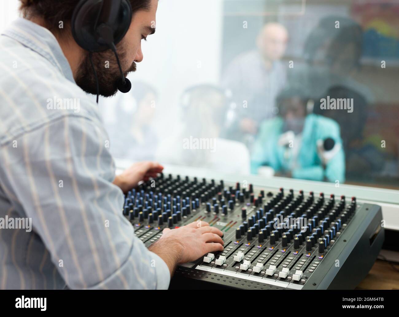 Professional sound engineer regulating level of sound with studio mixer ...