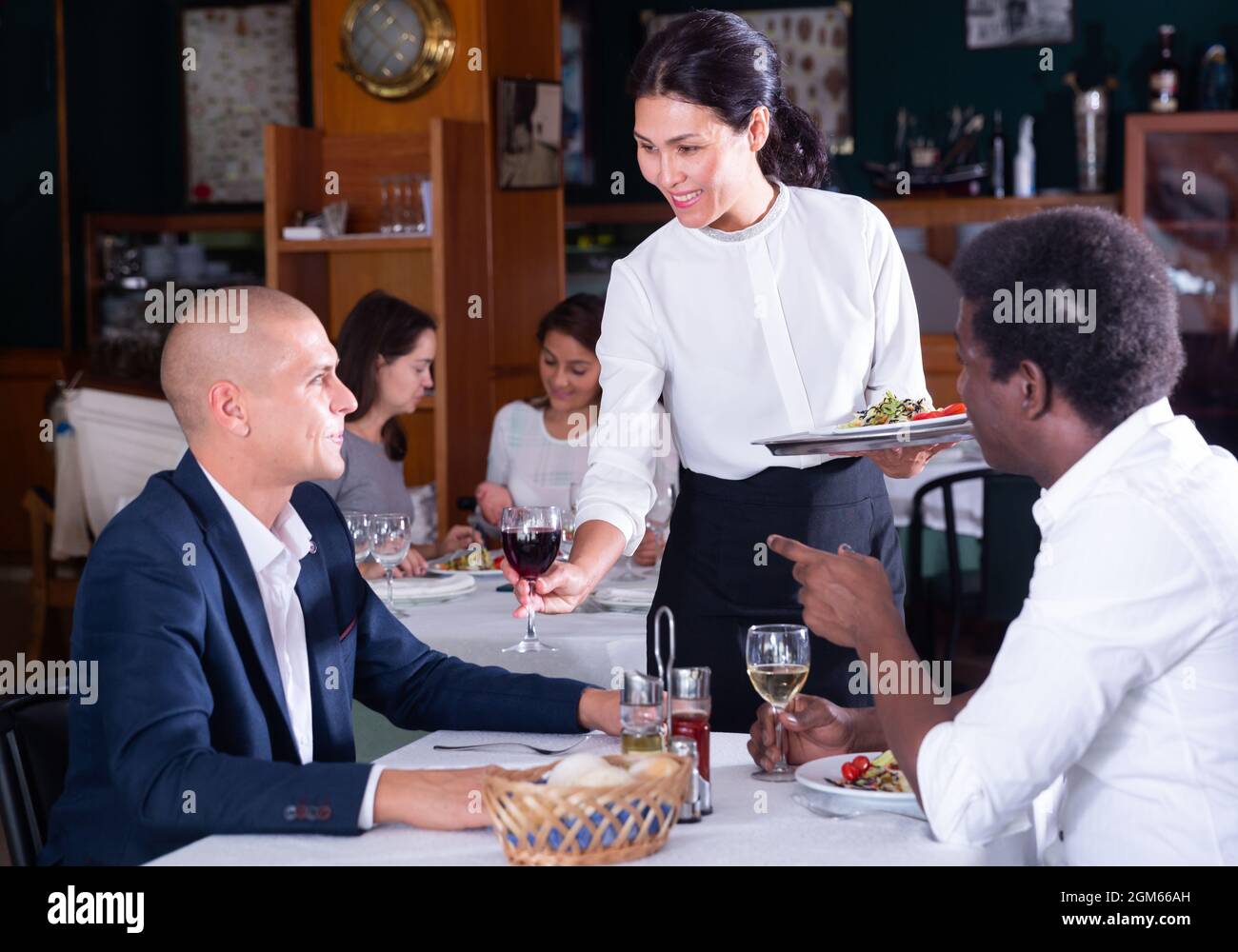 female waitress serving order from male customers in cafe Stock Photo ...