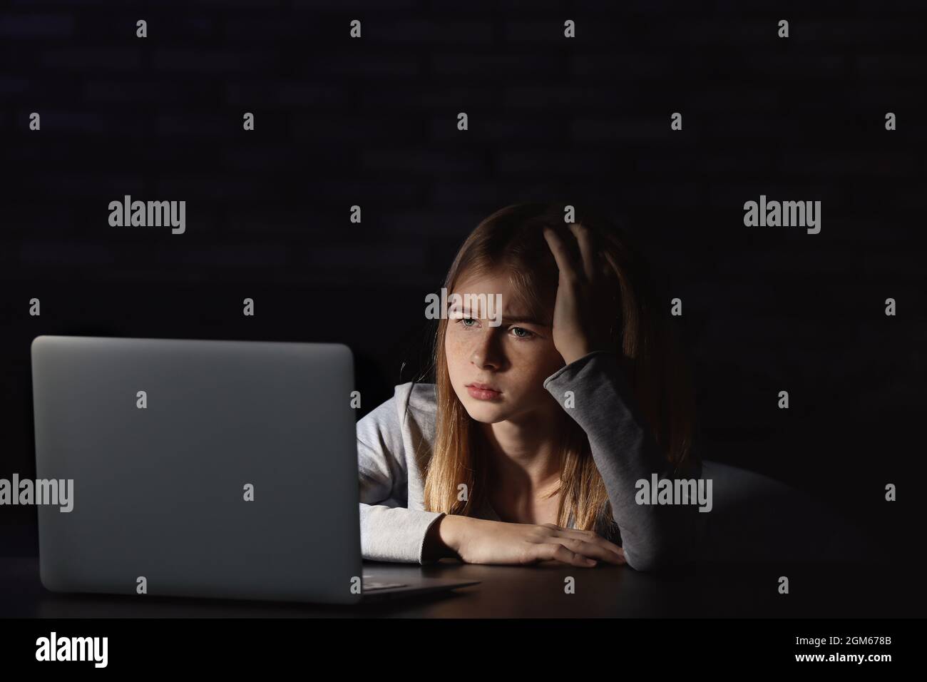 Sad teenage girl sitting near laptop in dark room Stock Photo - Alamy