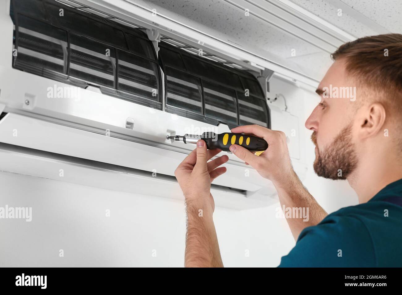 Male technician fixing air conditioner indoors Stock Photo - Alamy