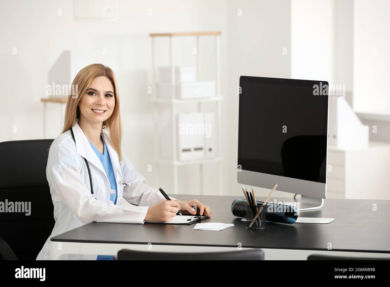 Female doctor filling up application form in consultation room Stock ...