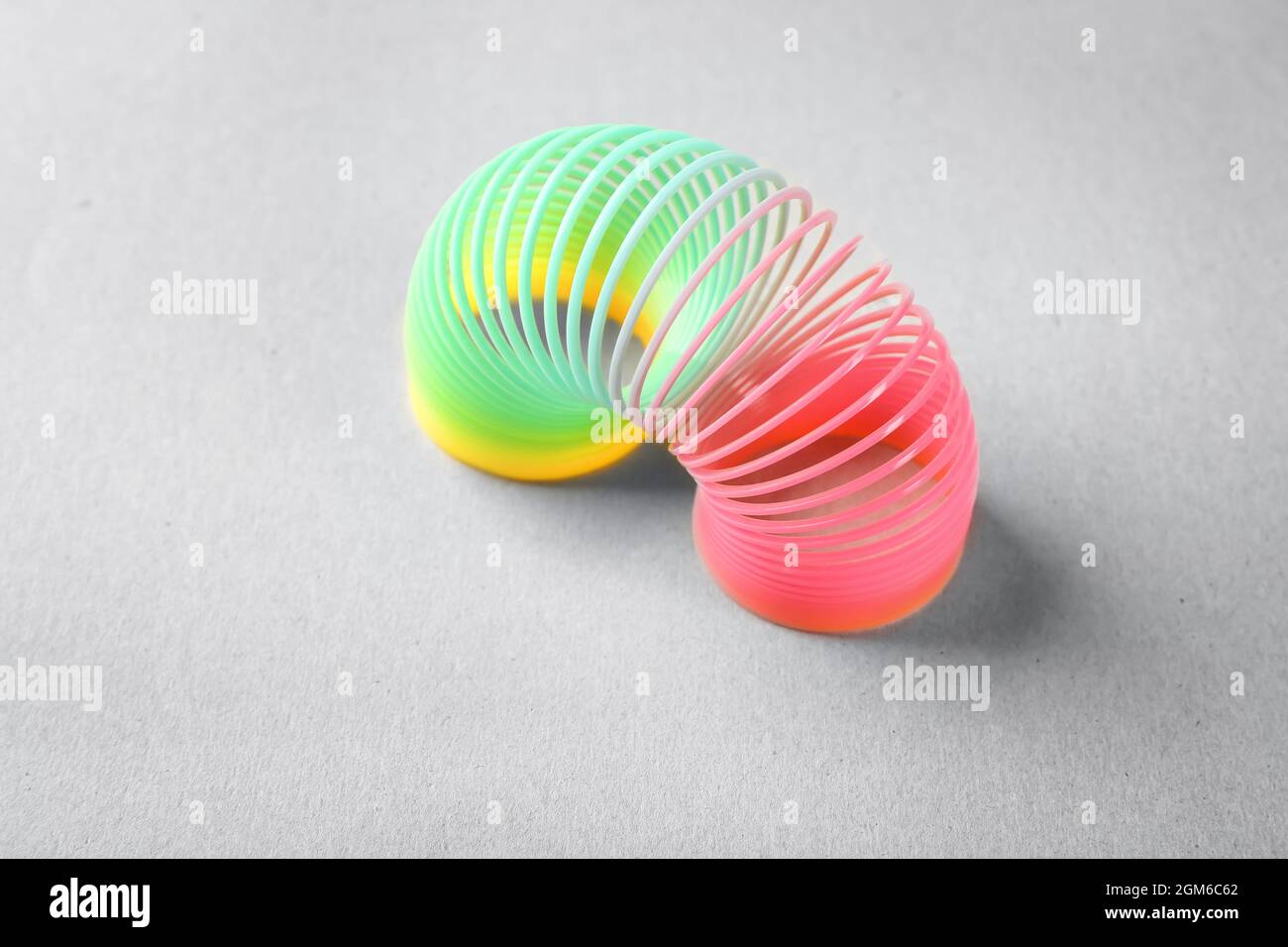 Rainbow slinky on grey background Stock Photo - Alamy