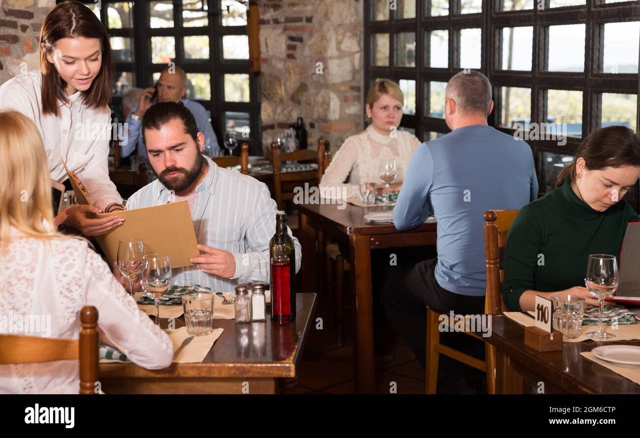 Female owner of restaurant helping guests with menu Stock Photo - Alamy