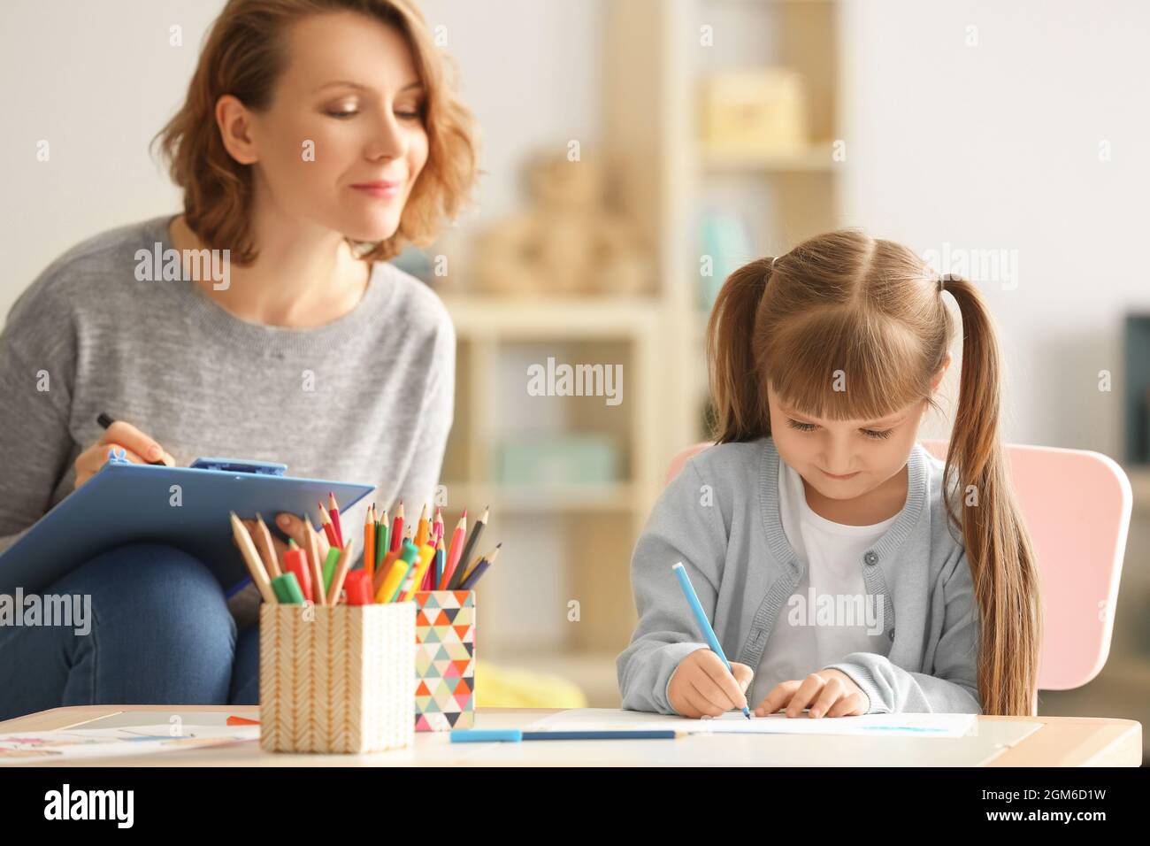 Female psychologist with cute little girl during art therapy Stock ...