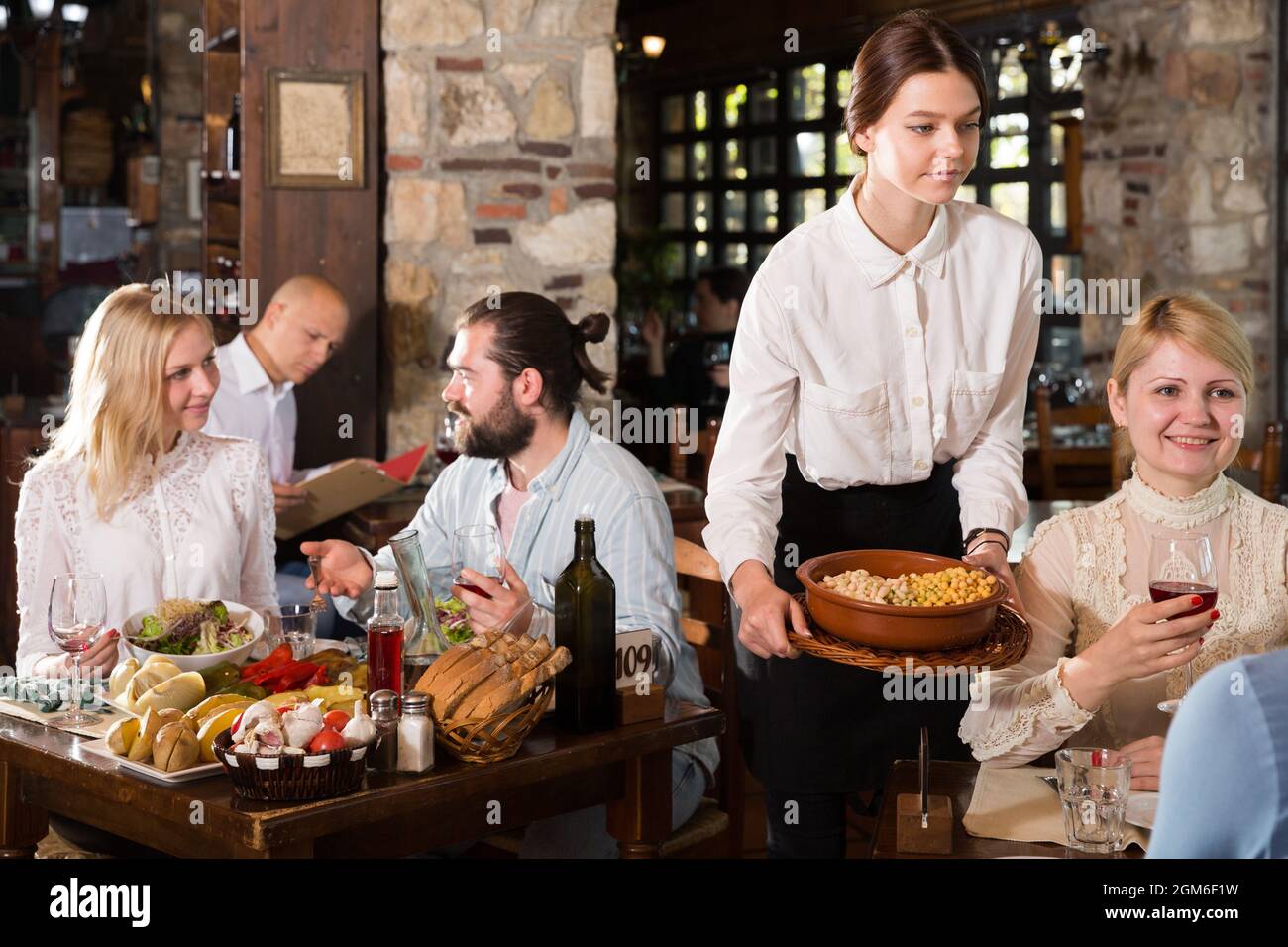 Female owner of rustic restaurant serving guests Stock Photo - Alamy