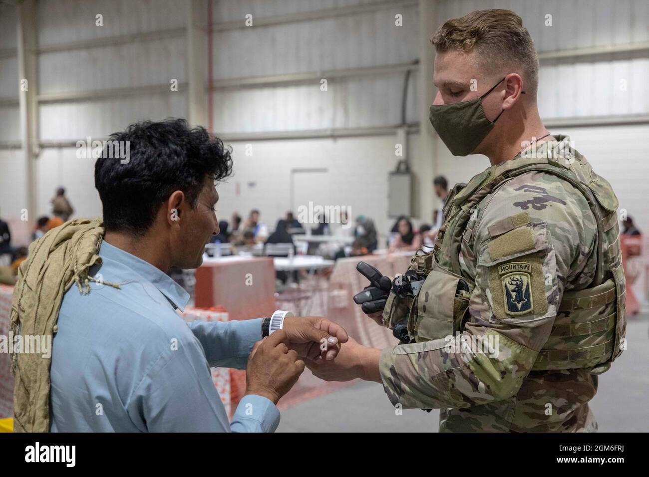 A U.S. Army Soldier assists an Afghan evacuee with his identification ...
