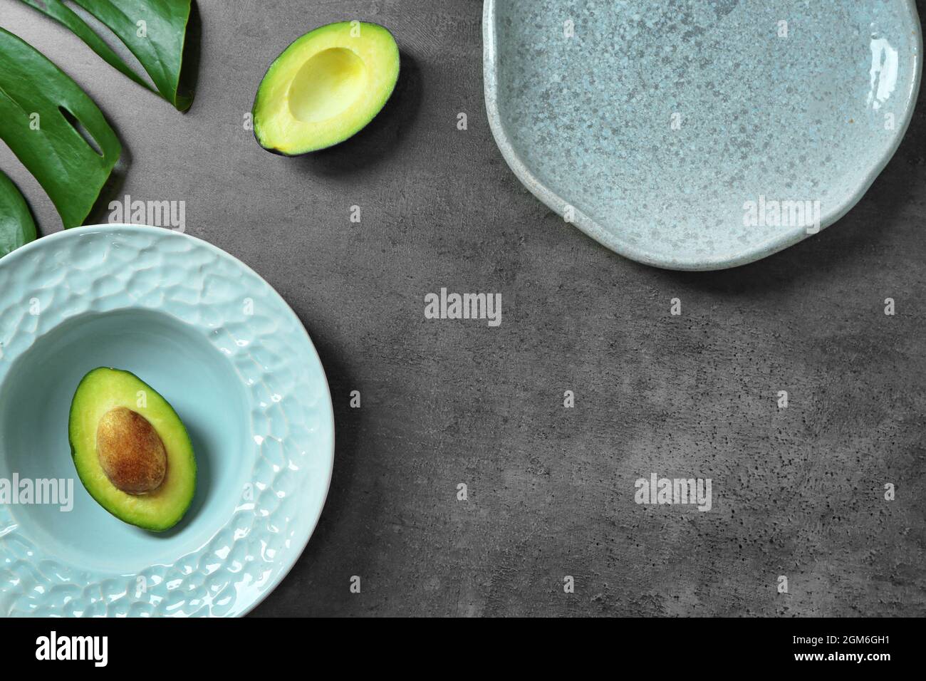 Ceramic plates and avocado on grey background Stock Photo - Alamy