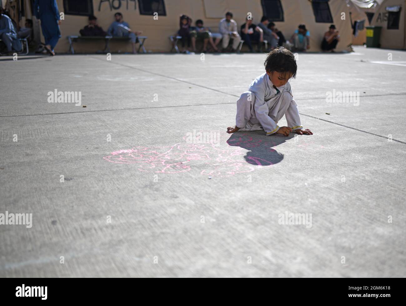 An evacuee draws on the flightline with pink chalk at Ramstein Air Base ...