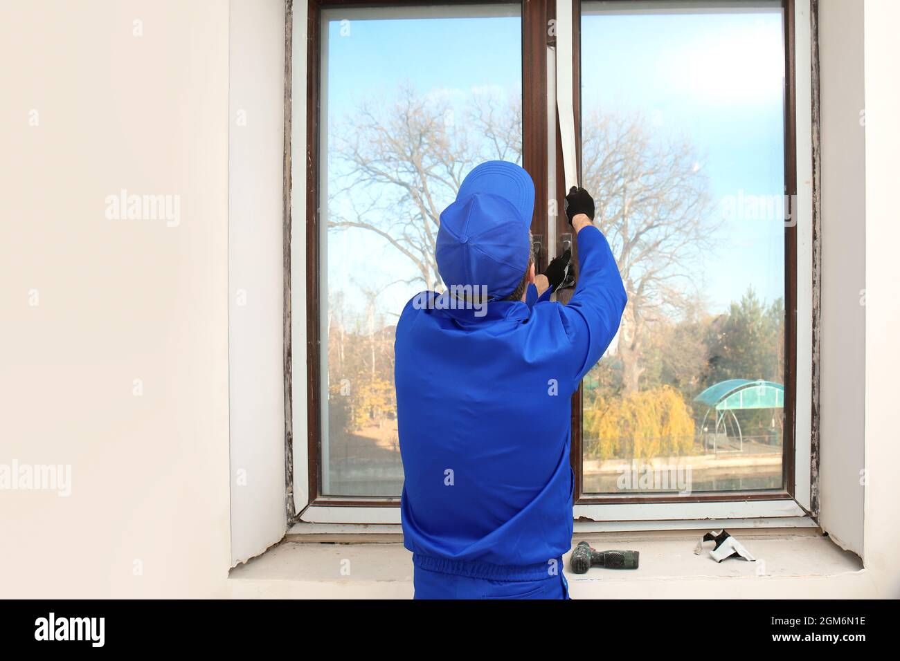 Construction worker removing sticky tape from window frame in house ...