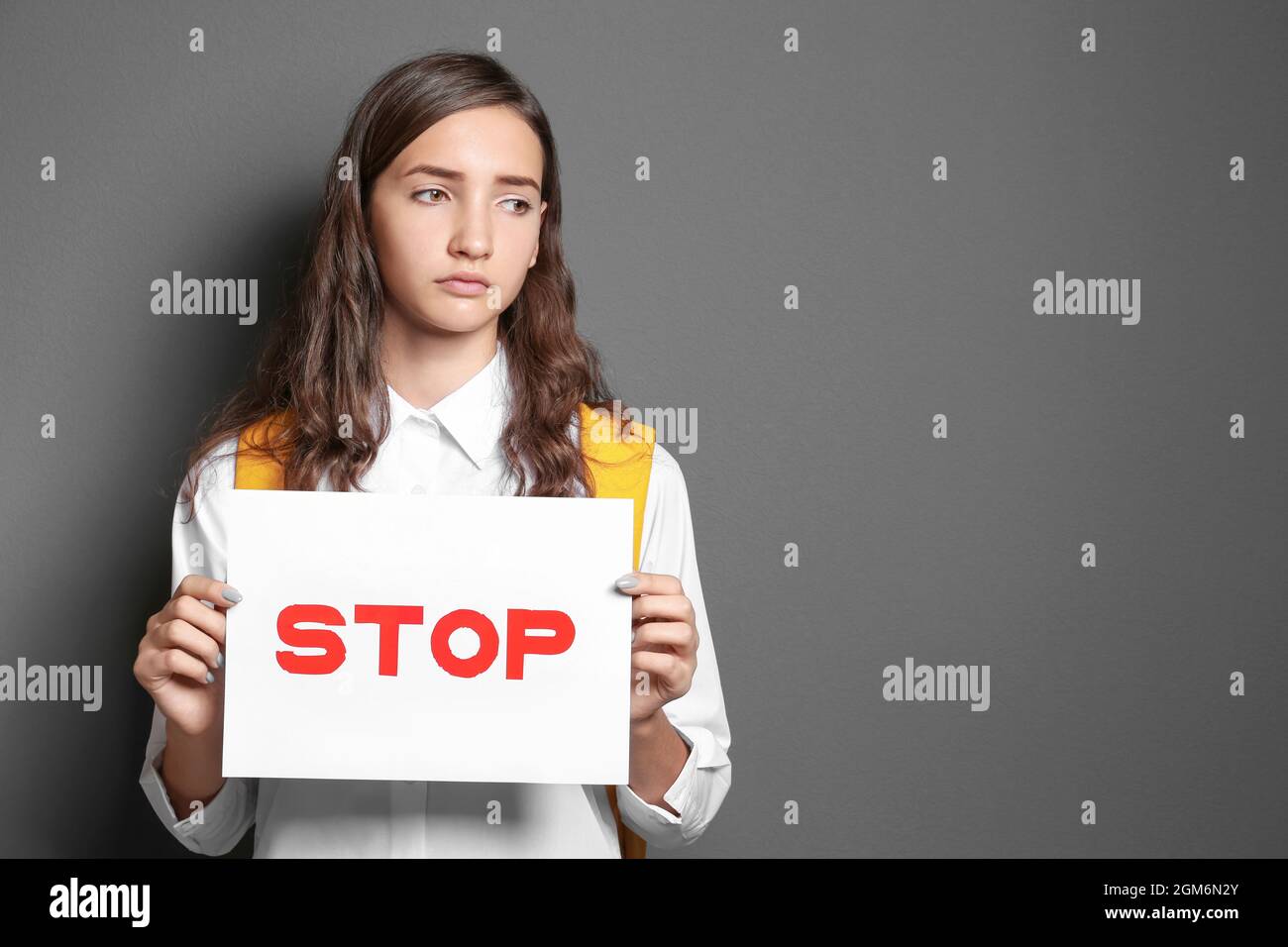 Teenage girl holding sign with word "Stop" on grey background Stock ...