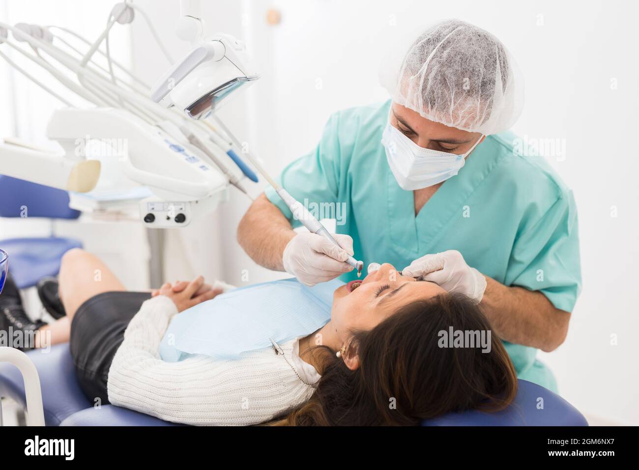 Male dentist drilling tooth to female patient Stock Photo - Alamy