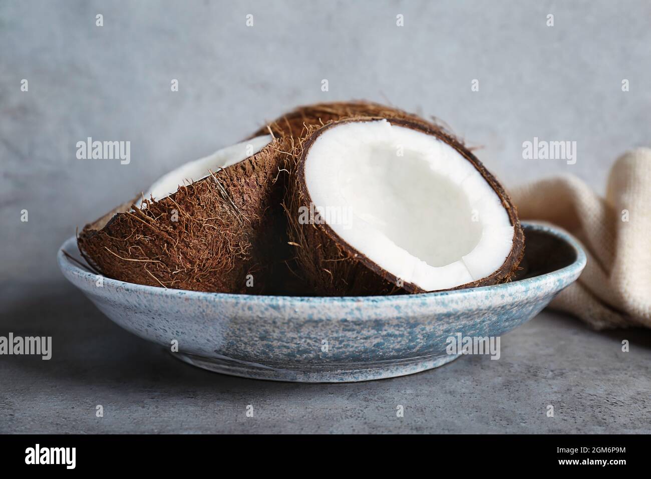 Plate with fresh coconuts on grey background Stock Photo - Alamy