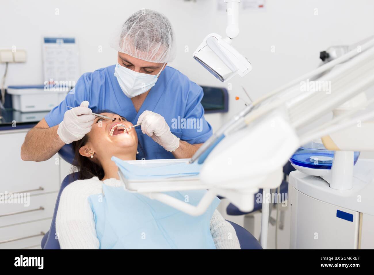 Dentist man examining a latin female patient teeth Stock Photo - Alamy