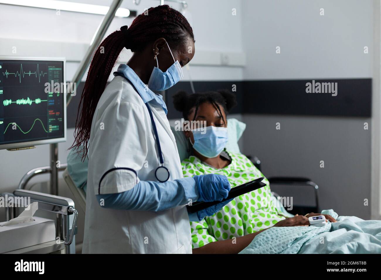 Medic of african ethnicity helping sick patient at clinic in hospital ...