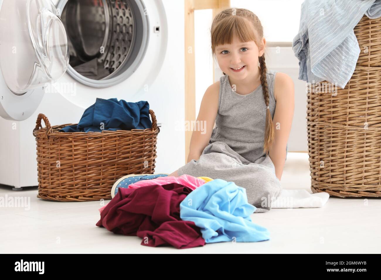 Cute little girl doing laundry indoors Stock Photo - Alamy
