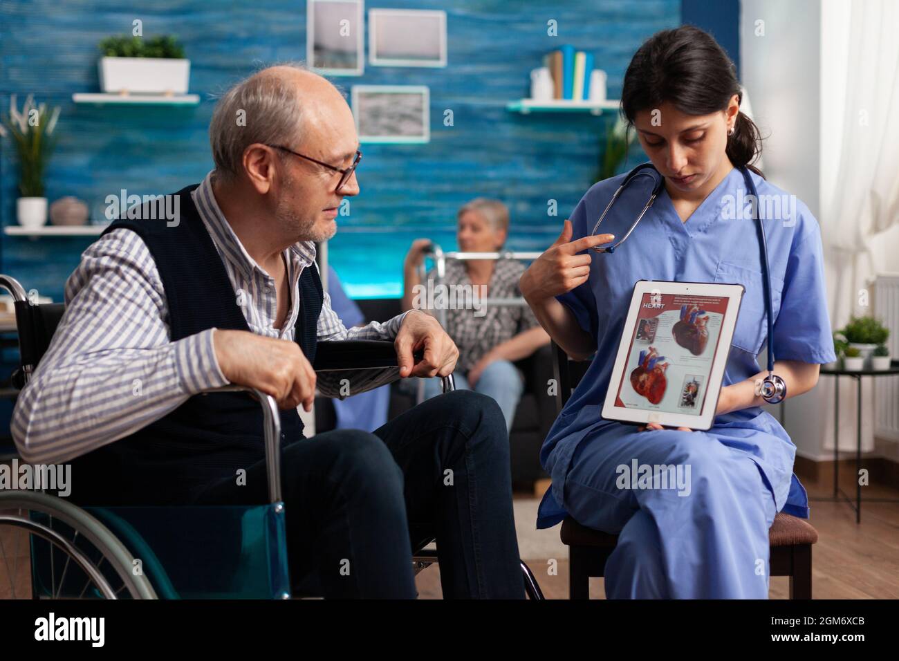 Social nurse worker explaining heart cardiogram radiography to retired ...