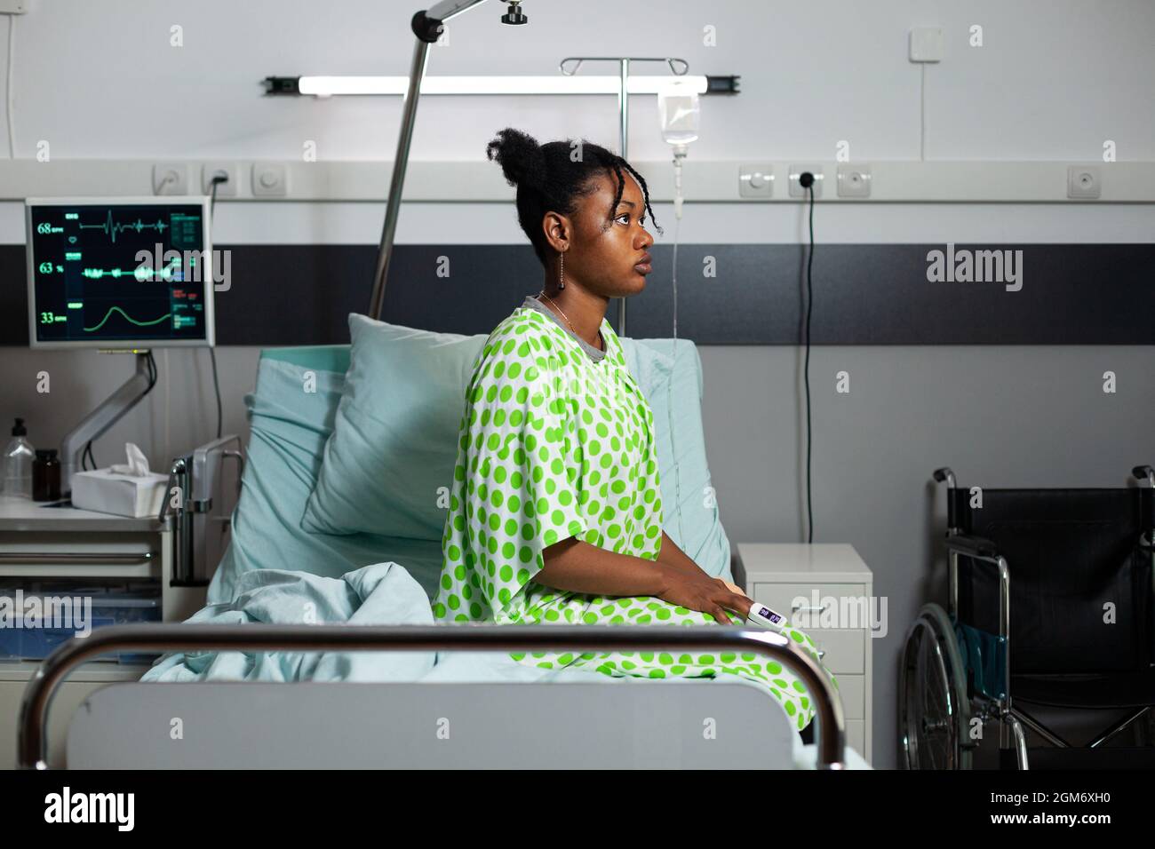 Young african american person sitting on hospital ward bed with fever ...