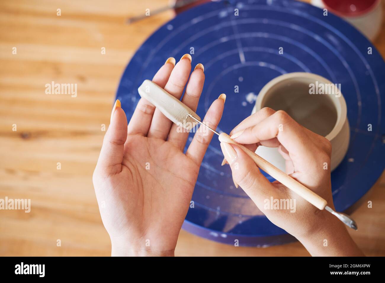 Hands of female ceramist carving handle of clay pot she created during ...