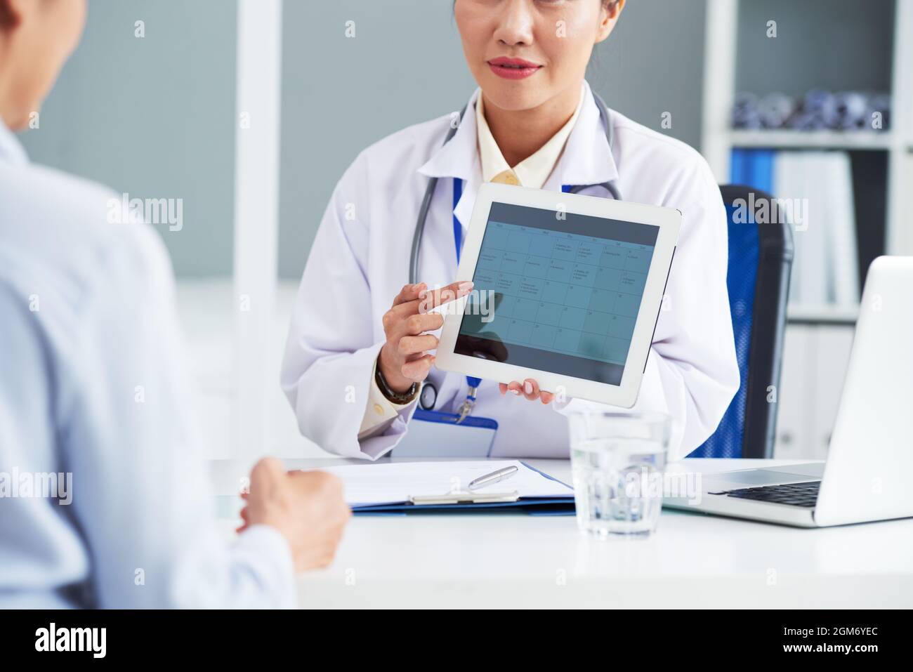Doctor showing calendar with her schedule to patient and asking to ...