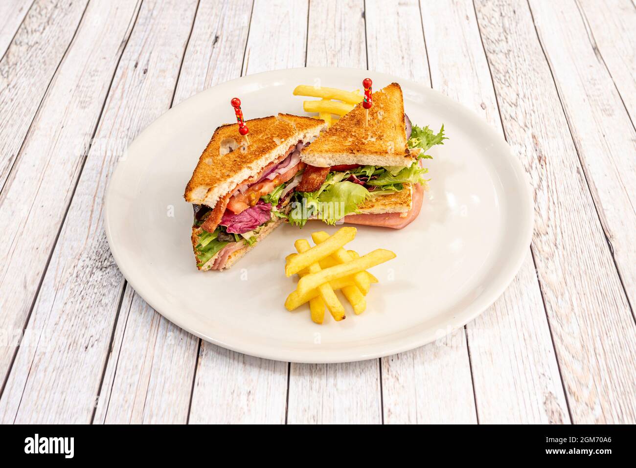 Typical club sandwich with layers of lettuce, sliced tomato, bacon, red ...