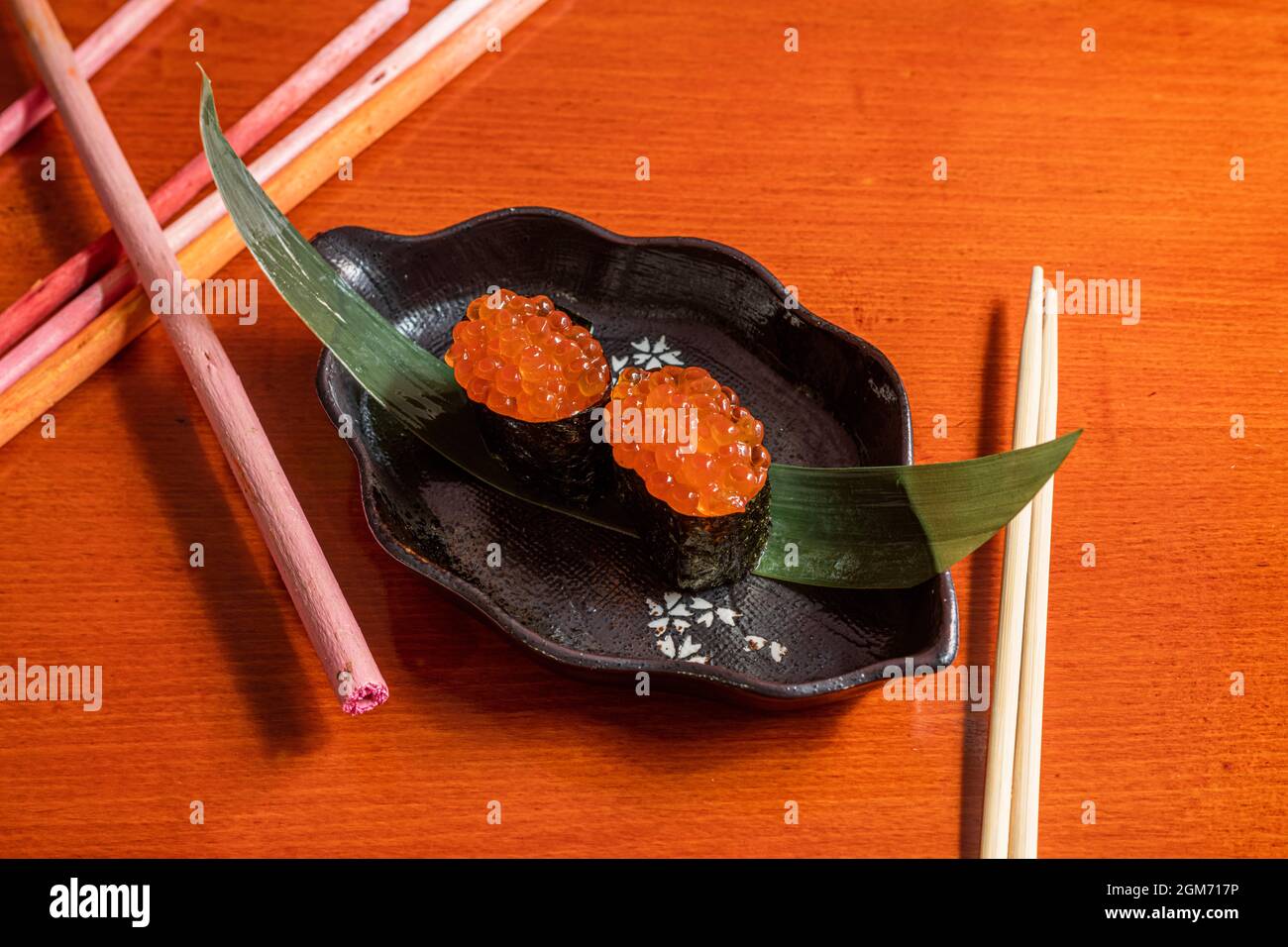 Norwegian salmon roe gunkan sushi, nori seaweed boat on banana leaf ...