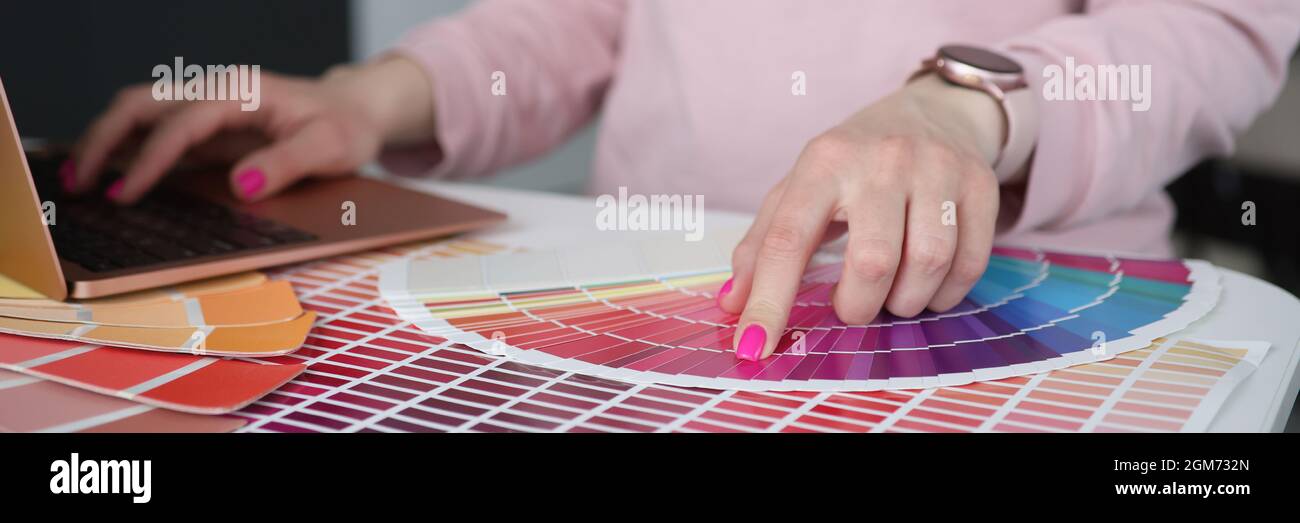 Designer typing on laptop keyboard and choosing color in palette ...