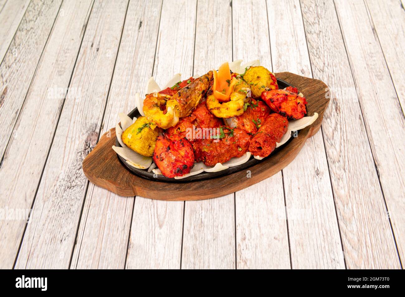 tandoori chicken skewer tray with prawns and a bed of white onions ...
