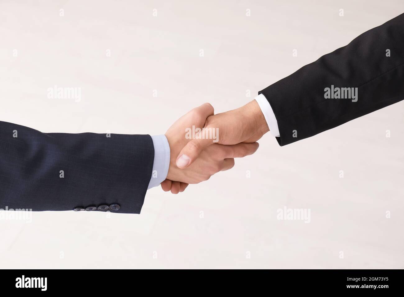 Two man shaking hands as symbol of unity on light background Stock ...