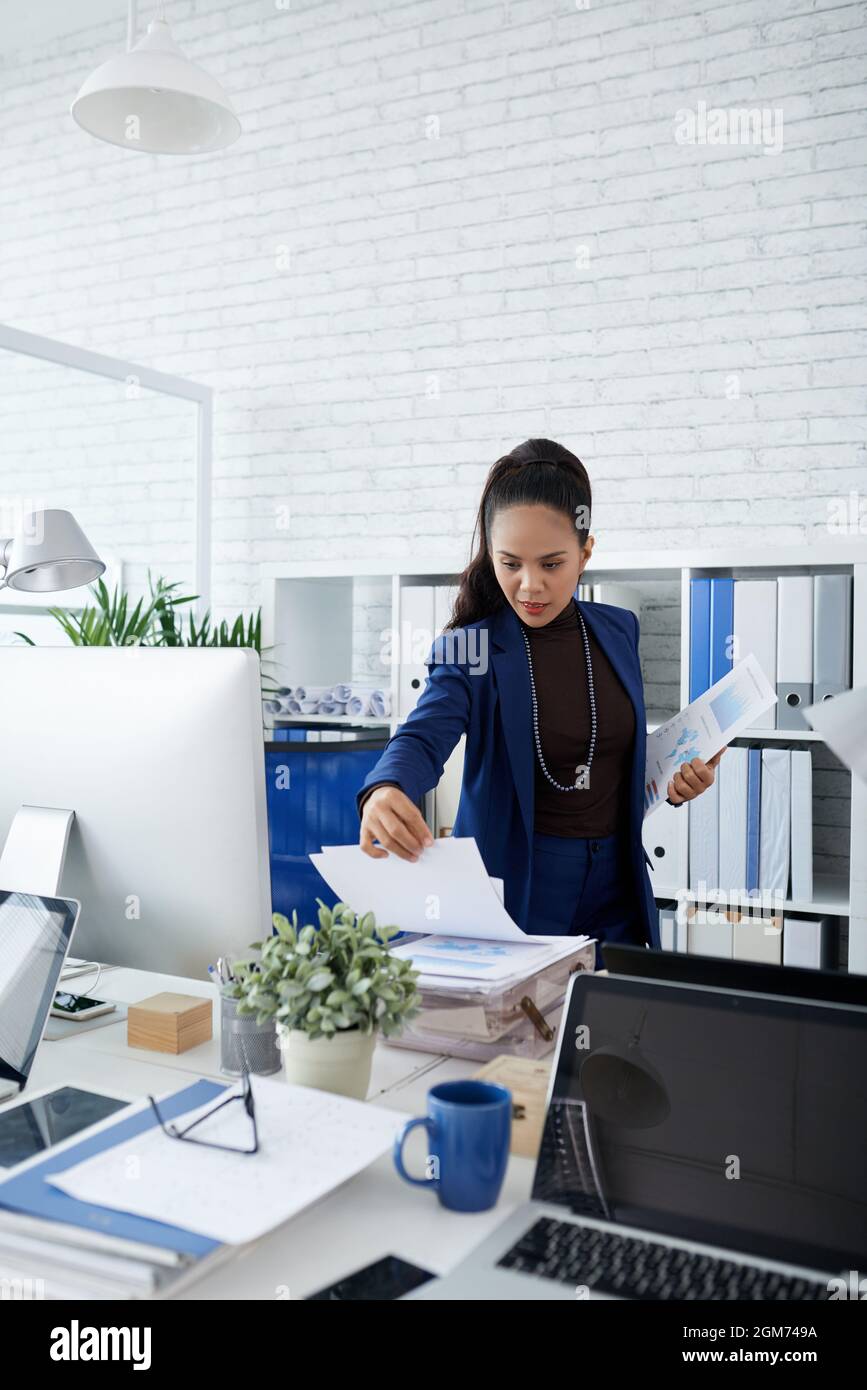 Business lady taking documents with charts and reports from stack next ...