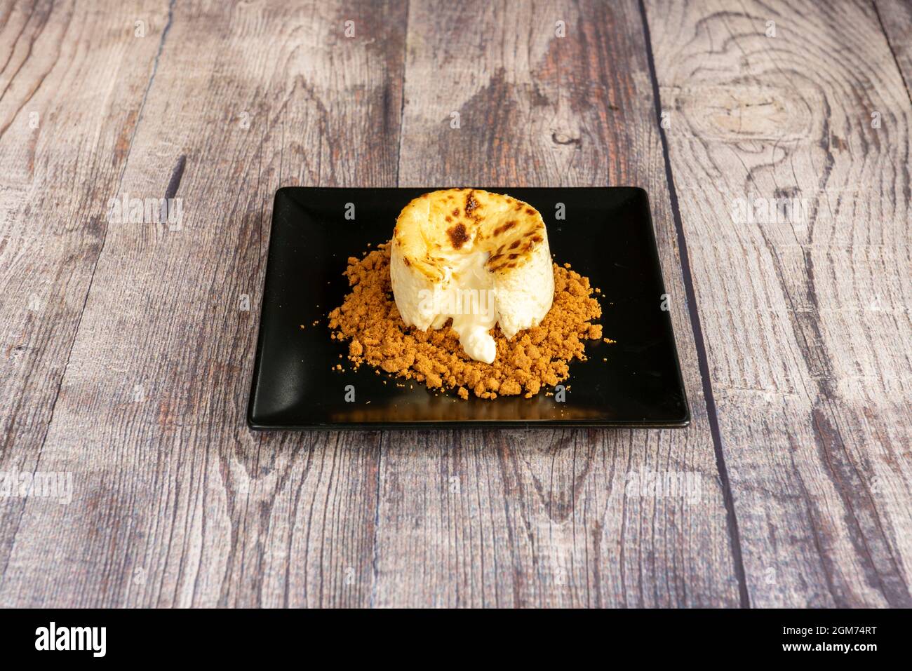 Cheesecake on cookie ground on black plate Stock Photo - Alamy
