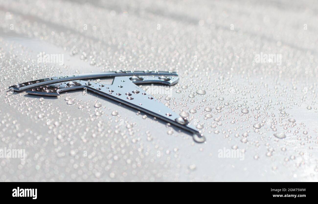 Tesla logo on the hood of a car with raindrops close up, electric car ...