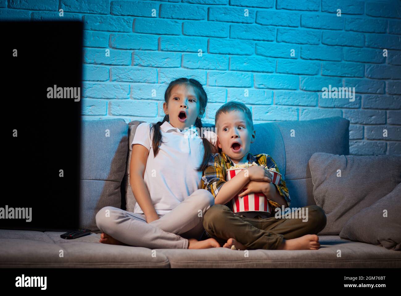 two children with remote control watching TV Stock Photo - Alamy