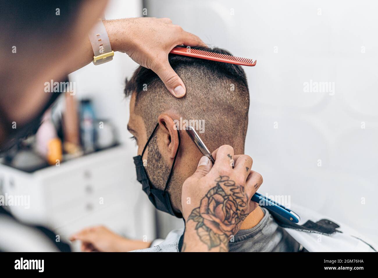 Barber shaving the hair of a man using a razor in a barber shop Stock ...