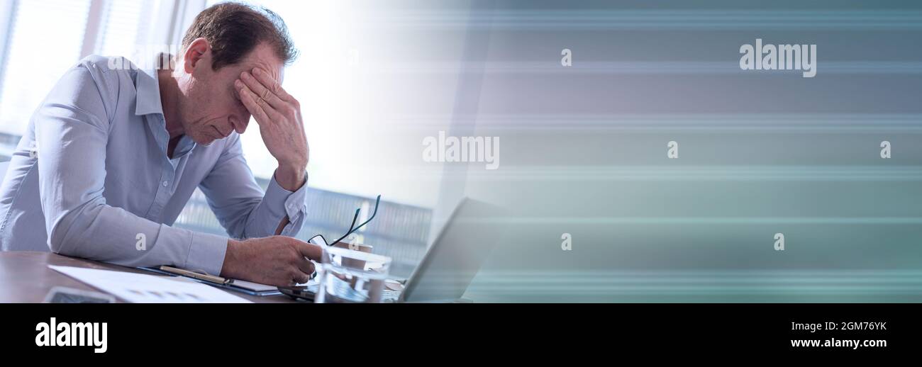 Stressed businessman sitting in office with hand on forehead. panoramic ...