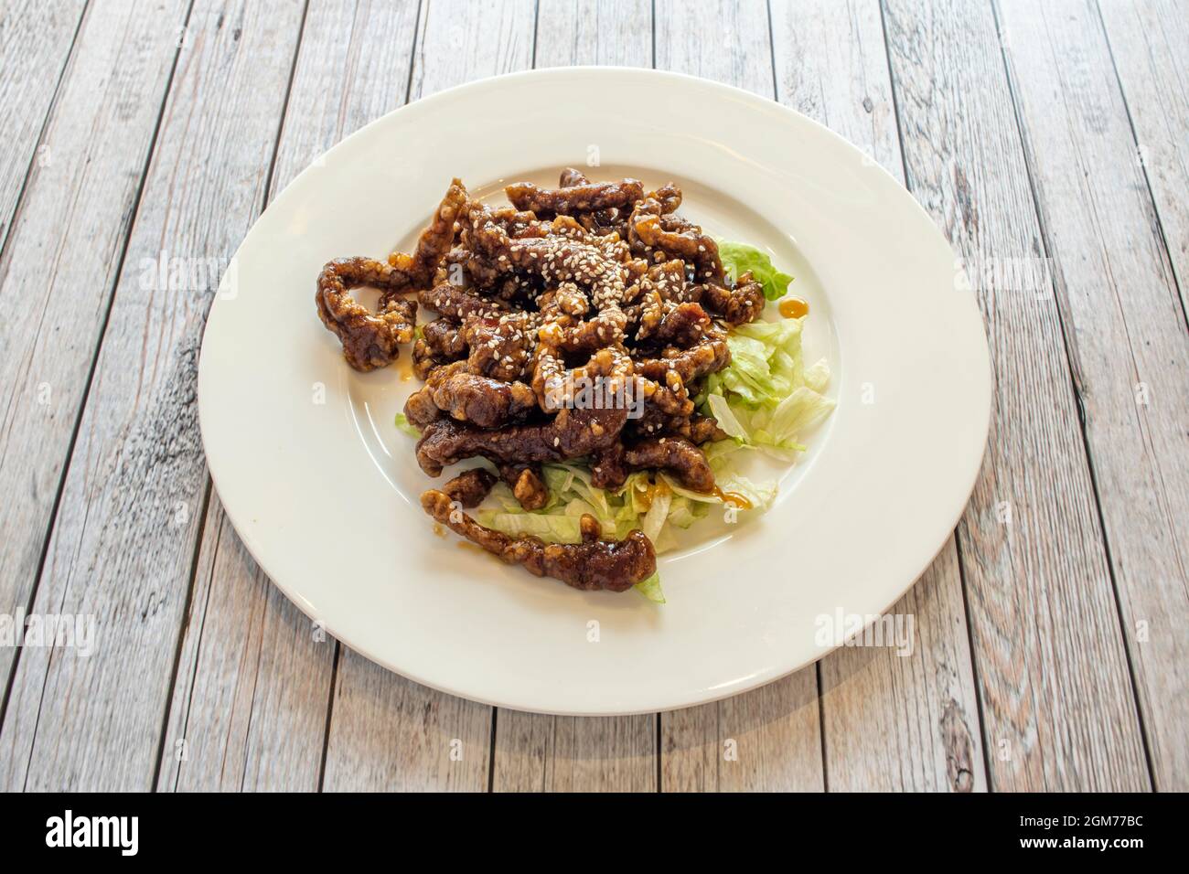 Crispy fried beef strips with sesame seeds and a bed of iceberg lettuce ...