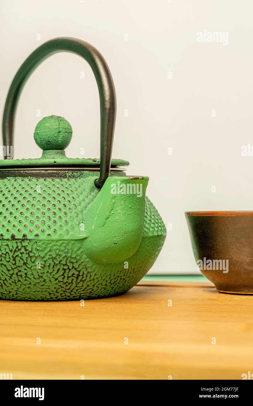 Traditional Asian style green cast iron teapot on a bamboo table and ...