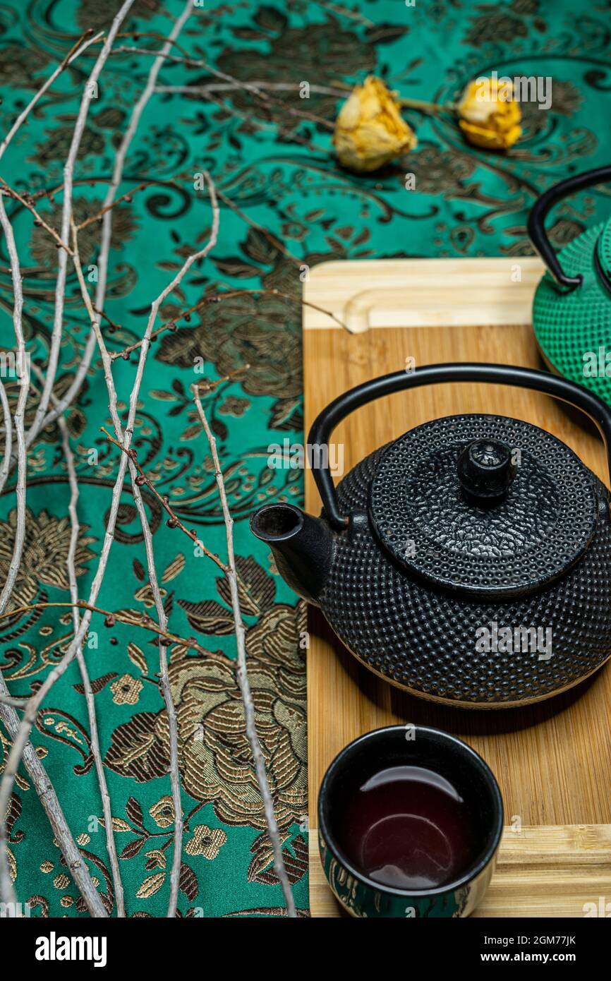 Chinese traditional tea set with branches and green cloth. Black cast ...