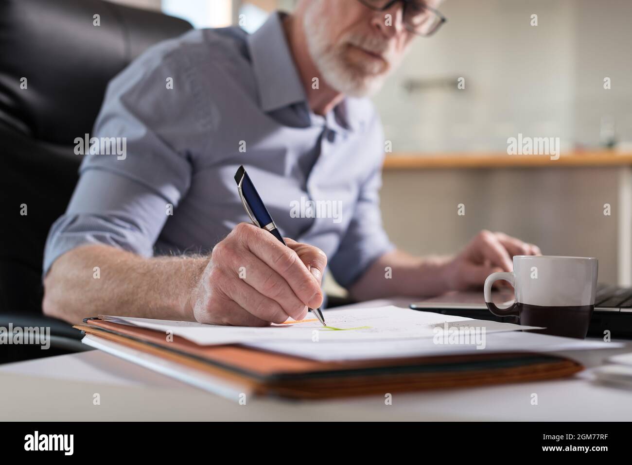 Senior businessman taking notes in office, hard light Stock Photo - Alamy