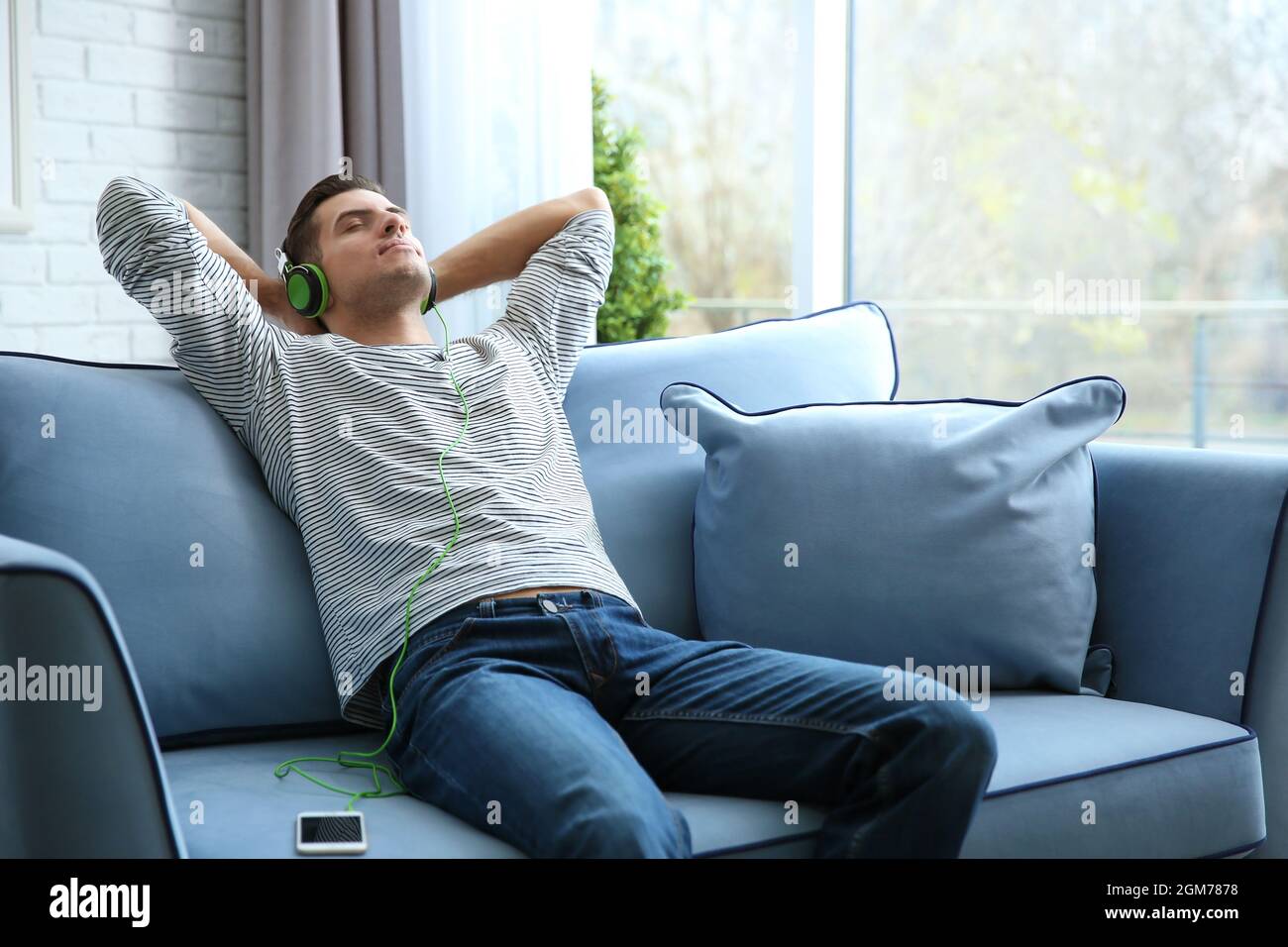 Relaxed young man listening to music at home Stock Photo - Alamy
