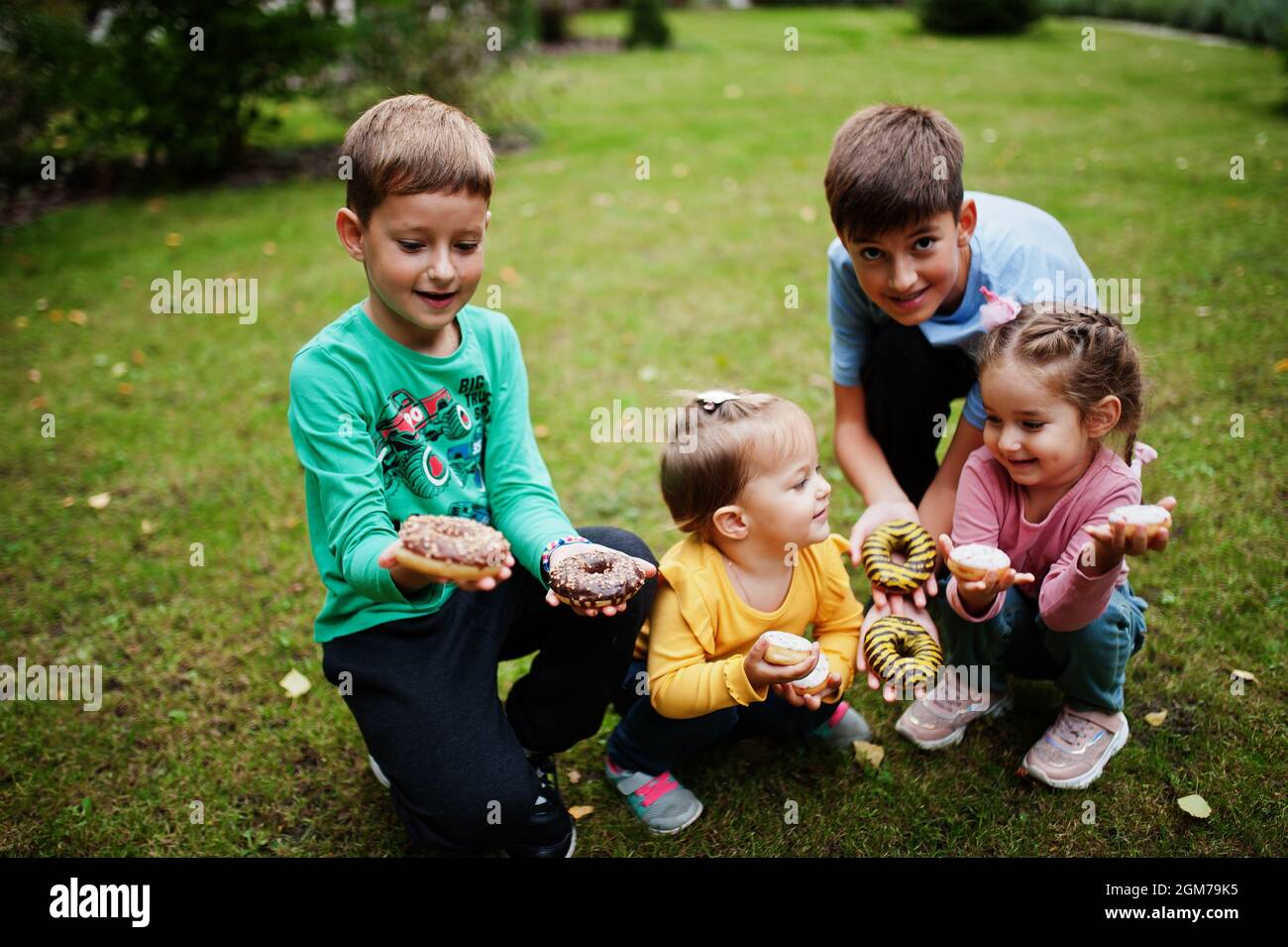 Four kids with doughnuts at evening yard. Tasty yummy donut food Stock ...