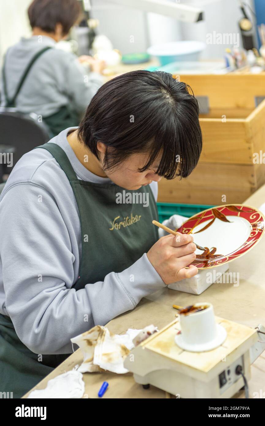 Female artist decorating plate at the pottery Craft Center in Noritake ...