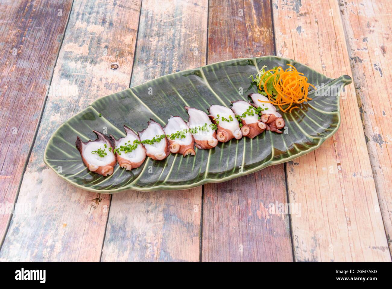 Cooked octopus tiradito with chopped fresh chives in a tray with the ...