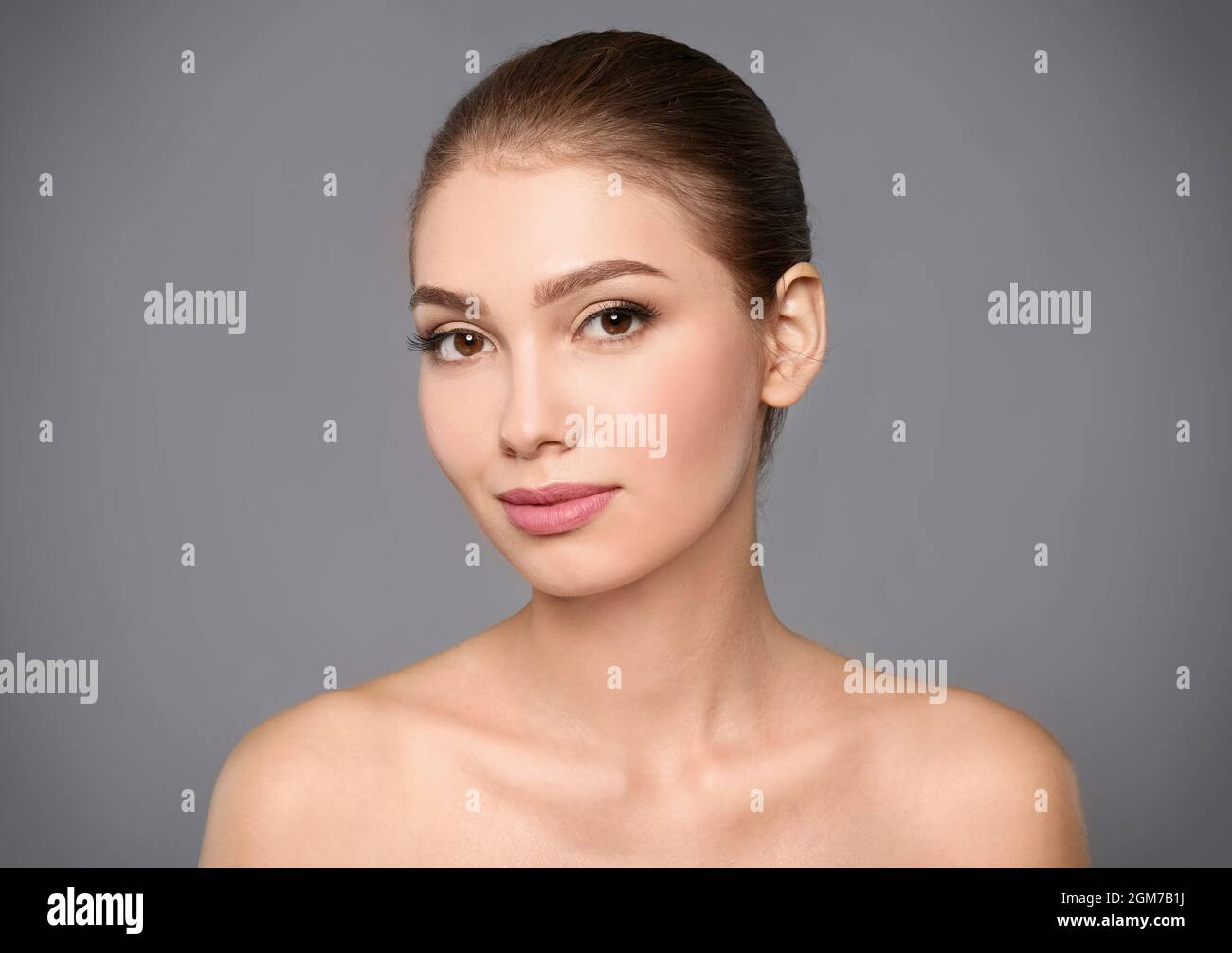 Portrait of beautiful young woman with clear skin on grey background ...